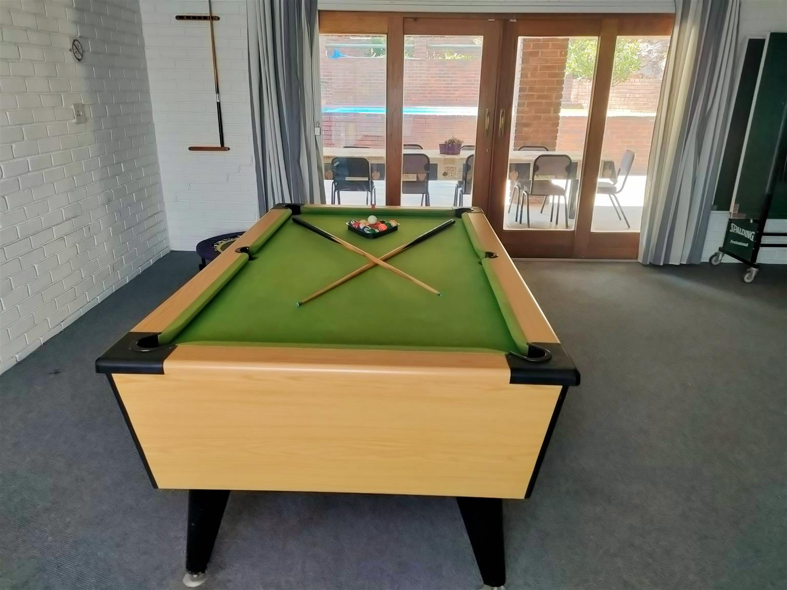 Solid oak pool table with green felt top.Two cues and cue stick holder ...